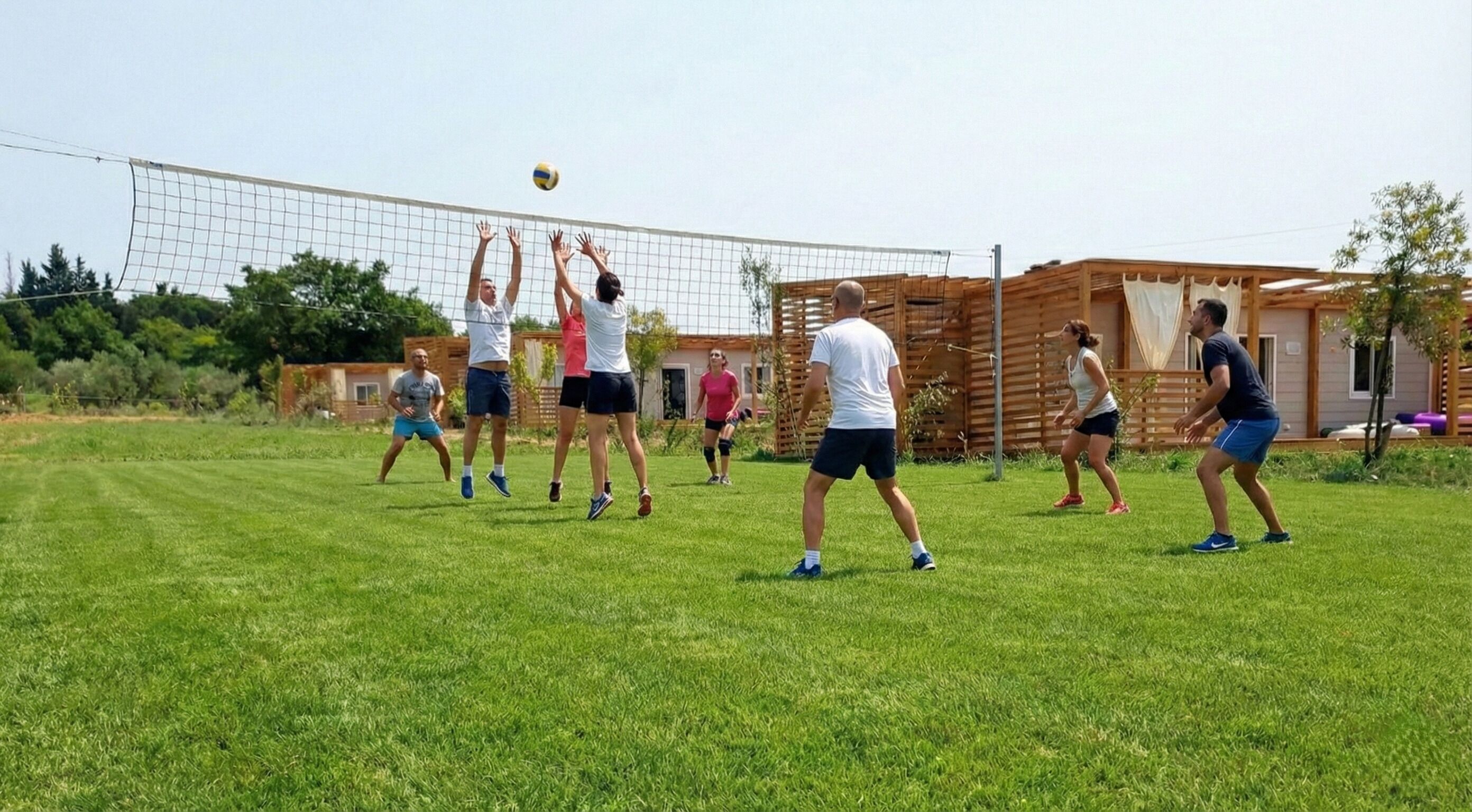 Um grupo de pessoas jogando voleibol em um campo gramado com uma rede.