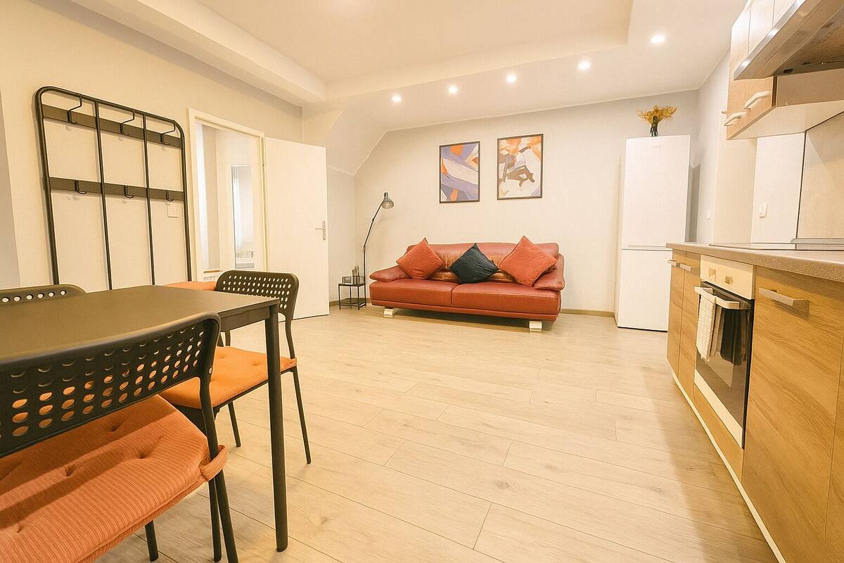 Um espaço compacto com área de refeições, um sofá, cozinha compacta e obras de arte nas paredes.