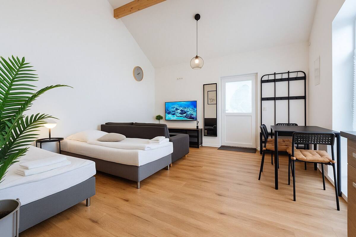 Quarto moderno e bem iluminado, com cama, televisão, mesa de jantar e beliche.