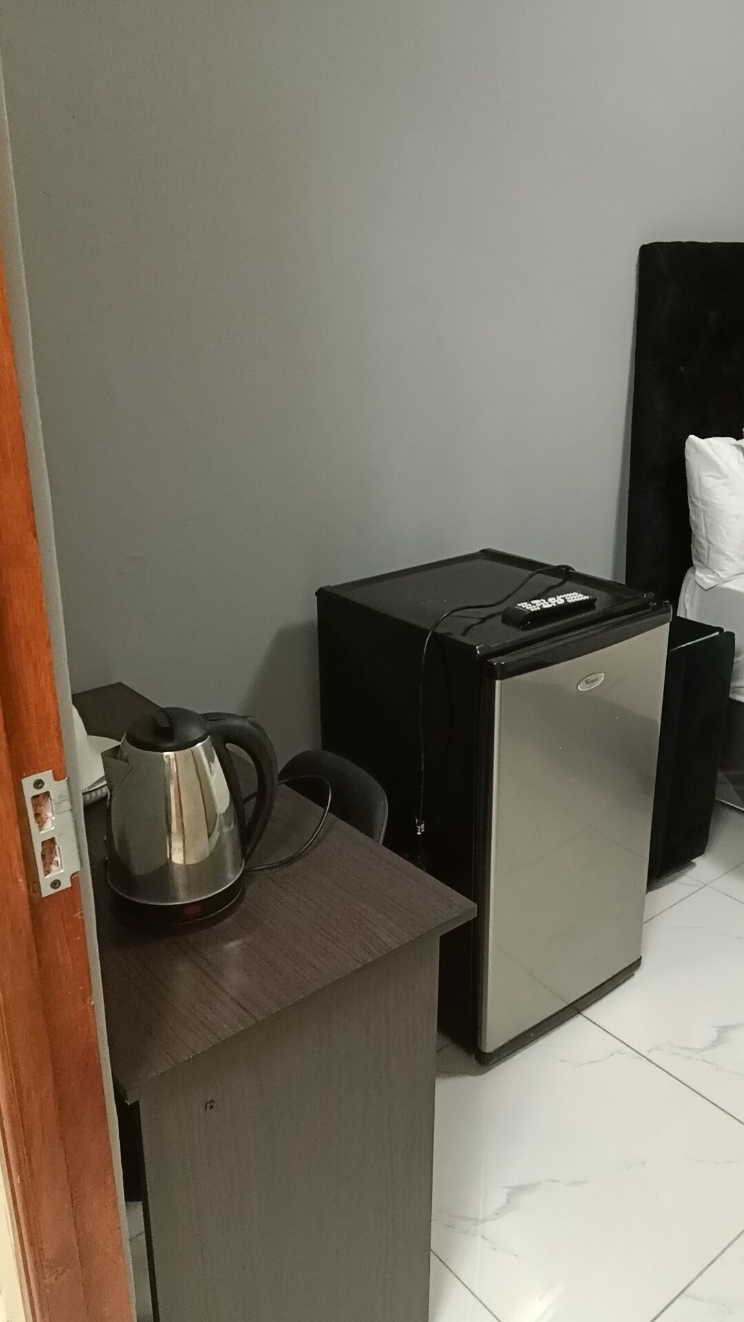 Quarto compacto com cozinha compacta, incluindo geladeira, chaleira e uma pequena mesa.