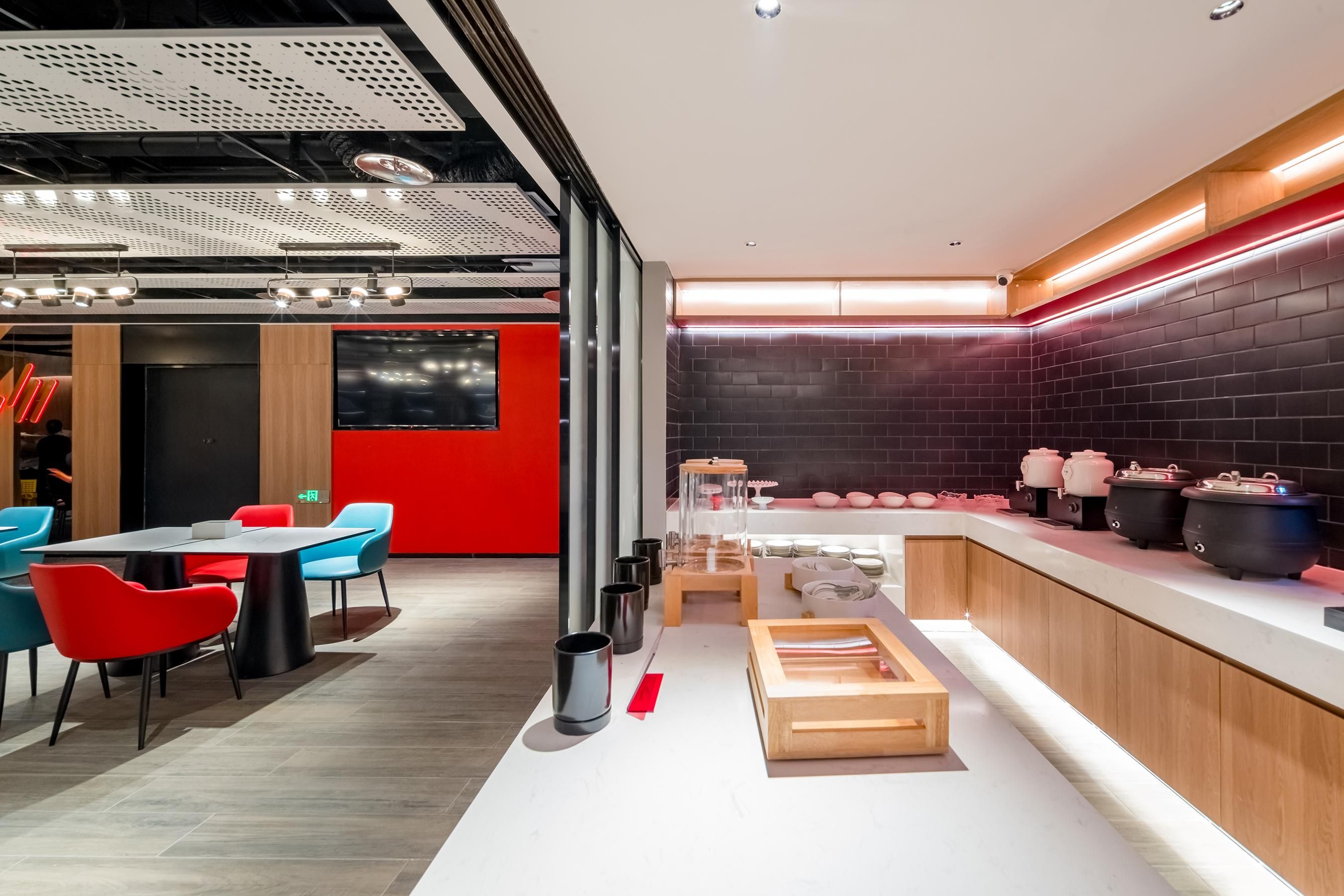 Cozinha moderna com bancada comprida, estrutura de vidro e diversos eletrodomésticos.