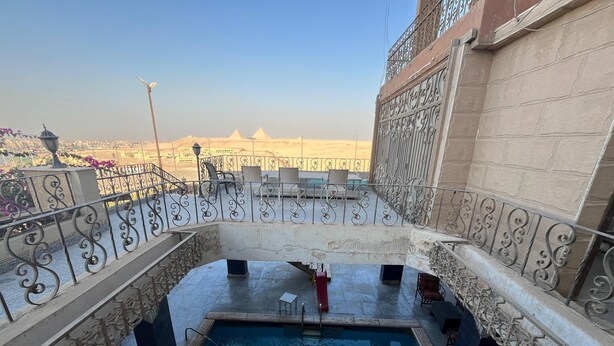 Piscina no terraço com vista para as pirâmides ao fundo.