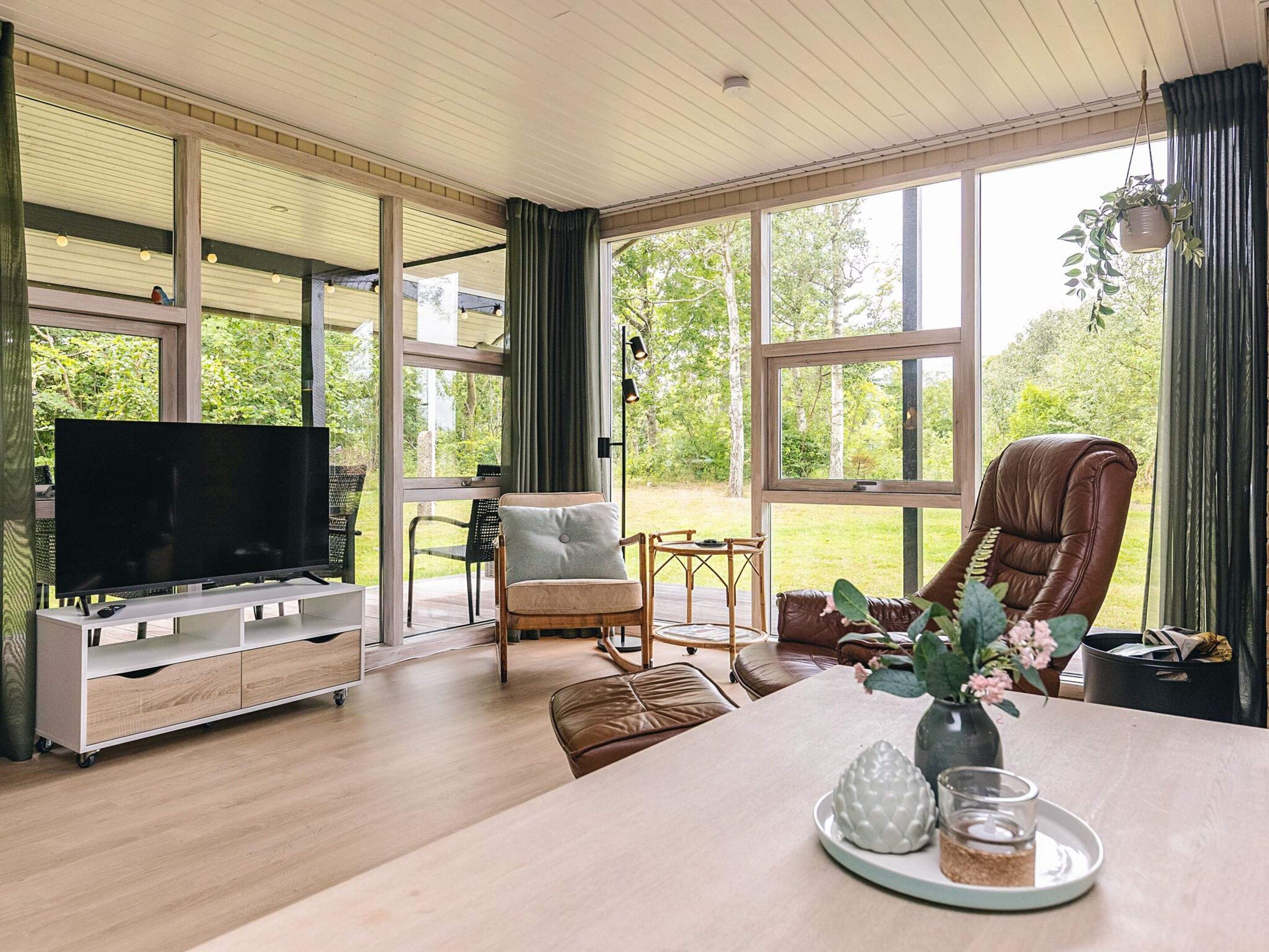 Uma sala de estar espaçosa com uma TV de tela grande, assentos confortáveis e vista para o exterior.