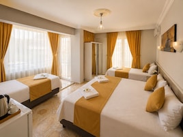 Quarto de hotel com duas camas, um minibar e uma janela grande com cortinas.