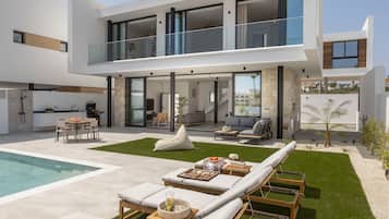 Uma casa moderna com dois andares, piscina, área de estar externa e gramado bem cuidado.