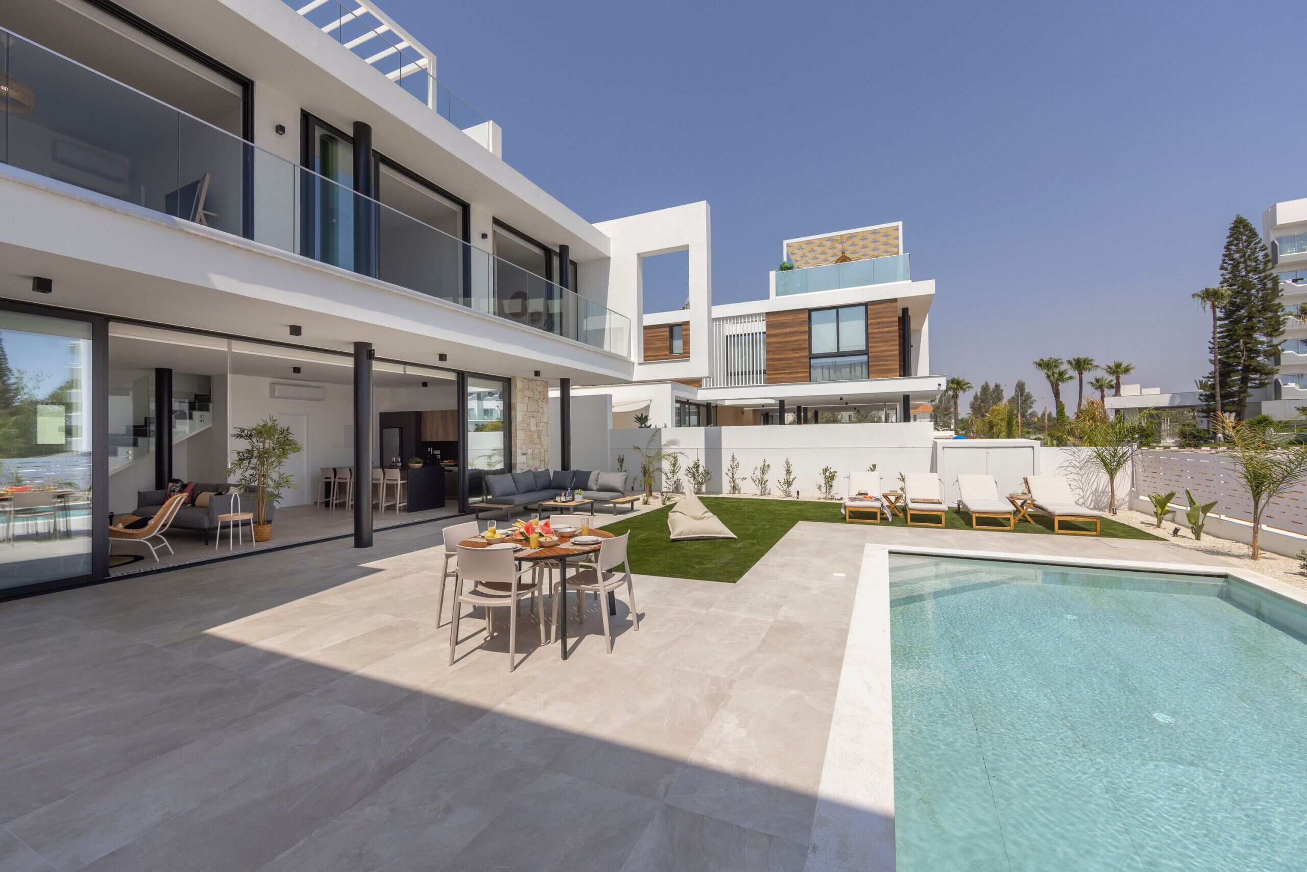 Uma casa moderna de dois andares com piscina, área de estar externa e gramado bem cuidado.