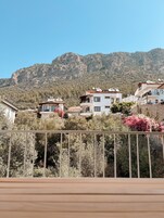 Um bairro residencial com casas, algumas com varandas, e montanhas ao fundo.