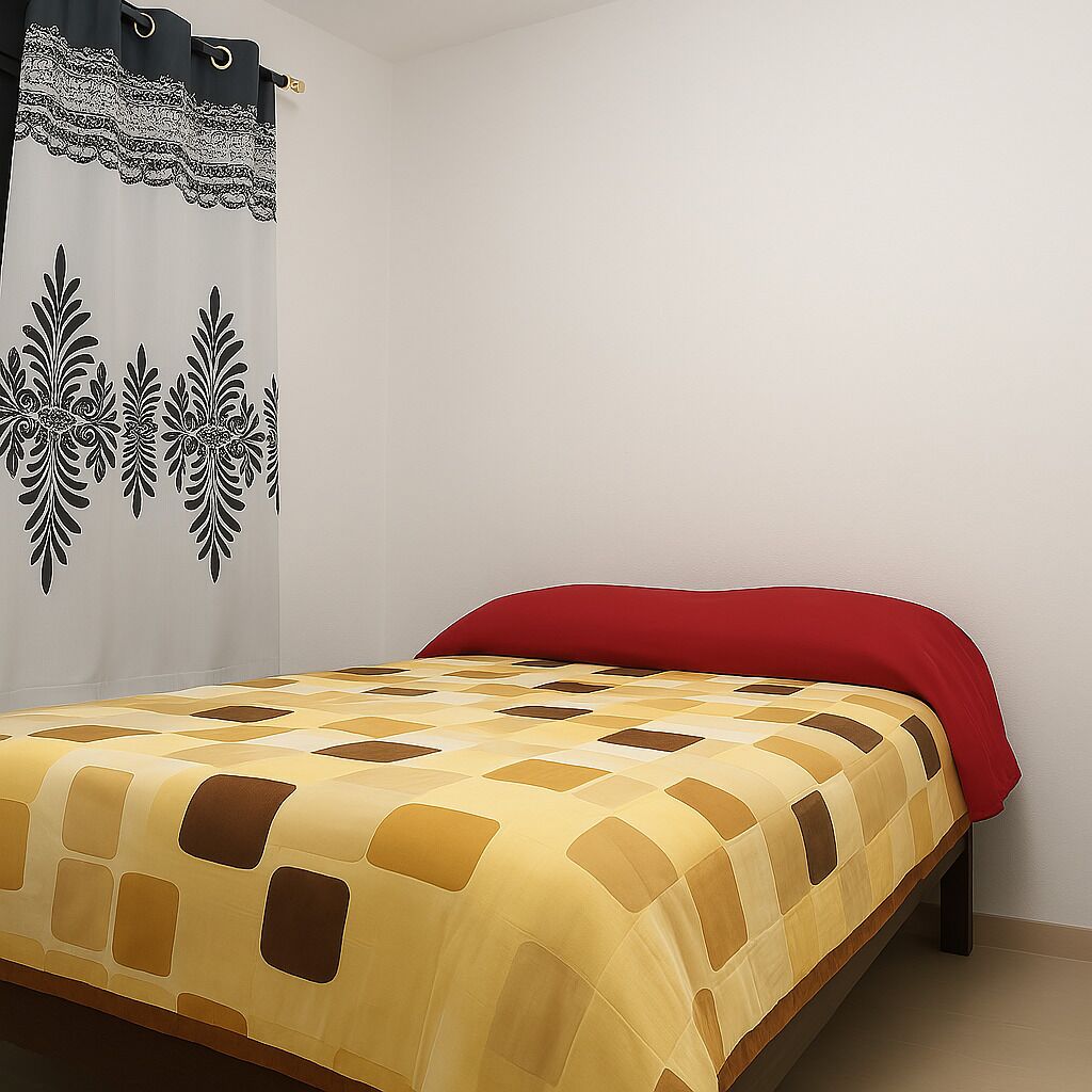 Uma cama com colcha de padrão geométrico, um travesseiro vermelho e uma cortina de renda preta e branca.