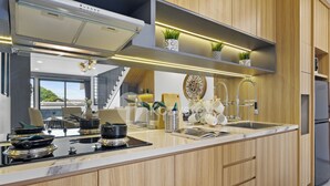 Cozinha moderna com armários de madeira, pia de aço inoxidável e fogão embutido.
