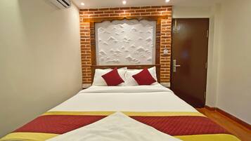 Quarto de hotel com uma cama grande, parede de tijolos e porta de madeira.