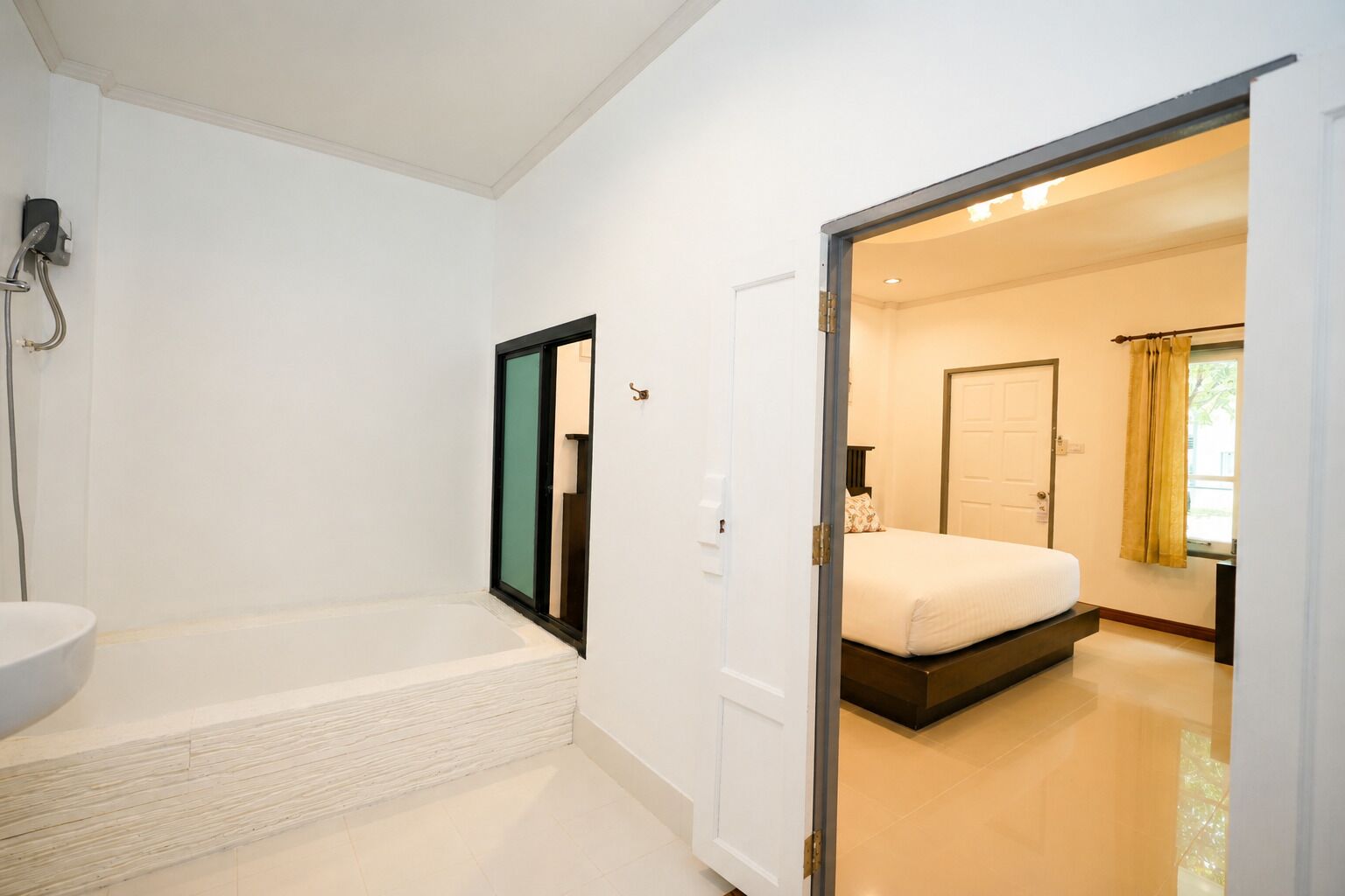 Quarto com banheira, cama e porta que dá para outro cômodo.