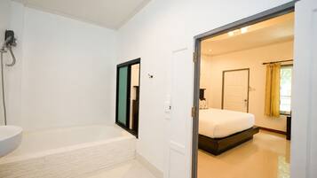 Quarto com banheira, cama e porta que dá para outro cômodo.