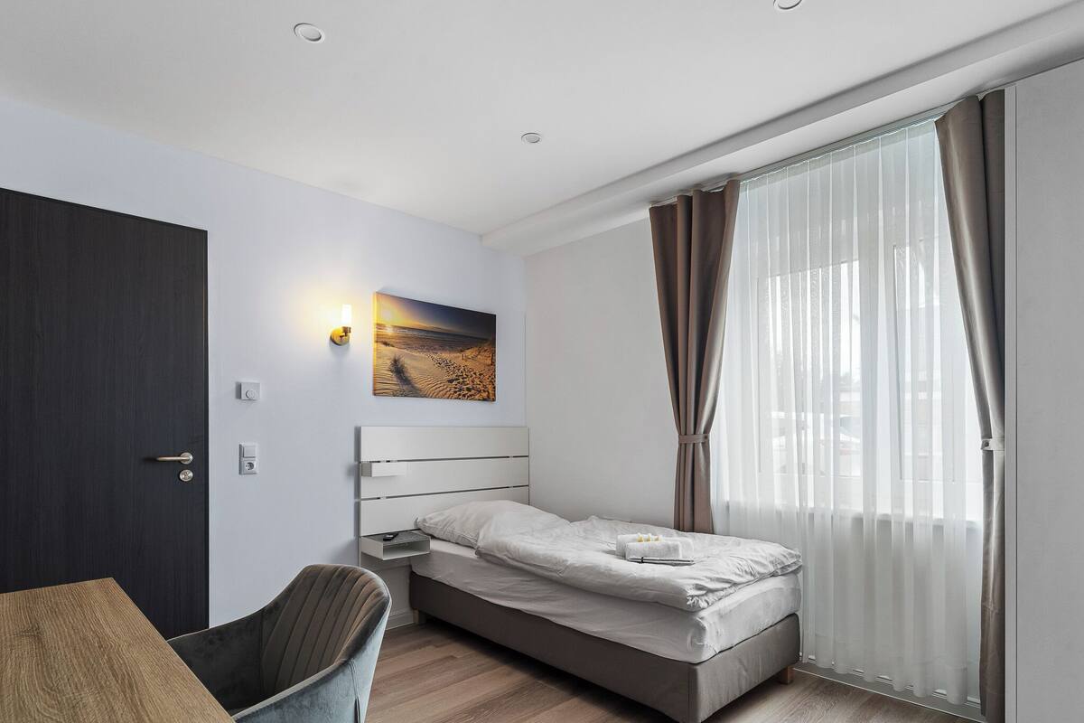Quarto de hotel moderno com uma cama, uma escrivaninha e uma cadeira.