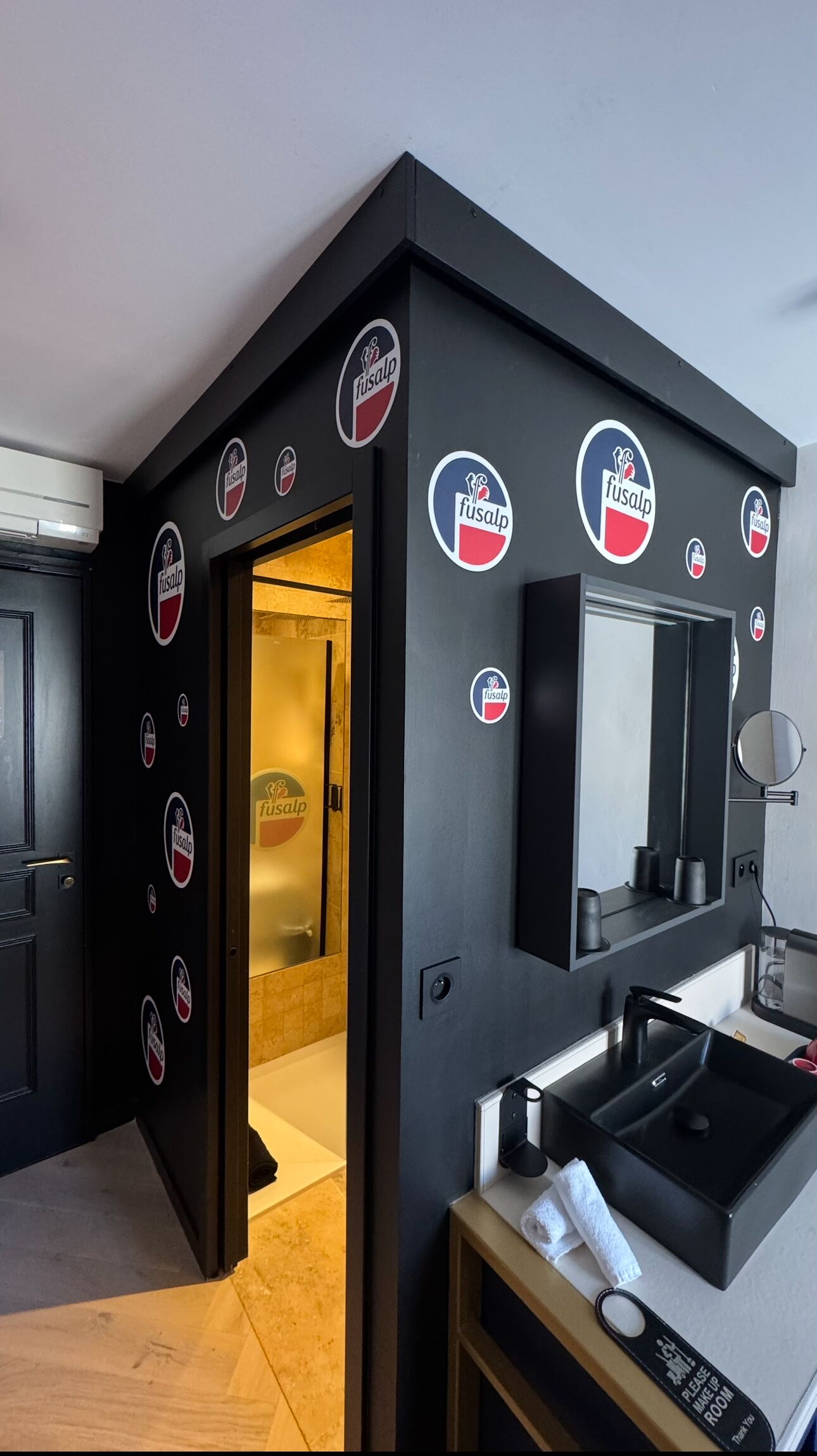 Uma casa de banho moderna com esquema de cores em preto e cinza, uma pia, espelho e porta-toalhas.