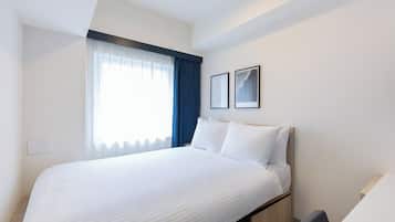 Quarto de hotel com uma cama grande, uma escrivaninha e uma janela com cortinas.