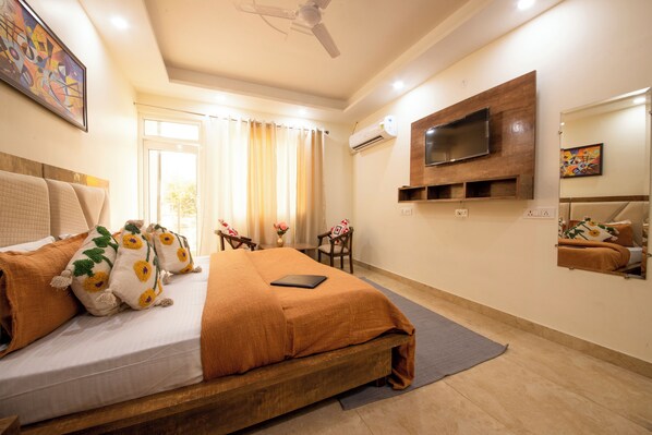 Quarto de hotel moderno com uma cama grande, televisão de tela plana na parede e ventilador de teto.