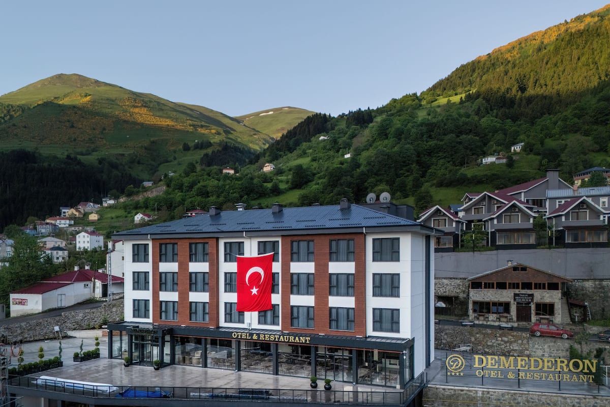 Um hotel com uma bandeira, rodeado por colinas e casas.