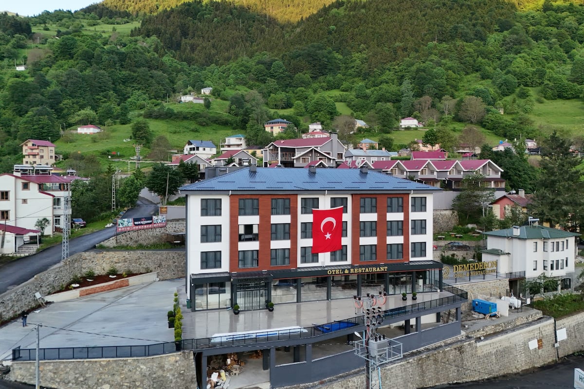Um hotel com uma bandeira vermelha chamativa, uma área externa coberta e vista para a comunidade arborizada ao redor.