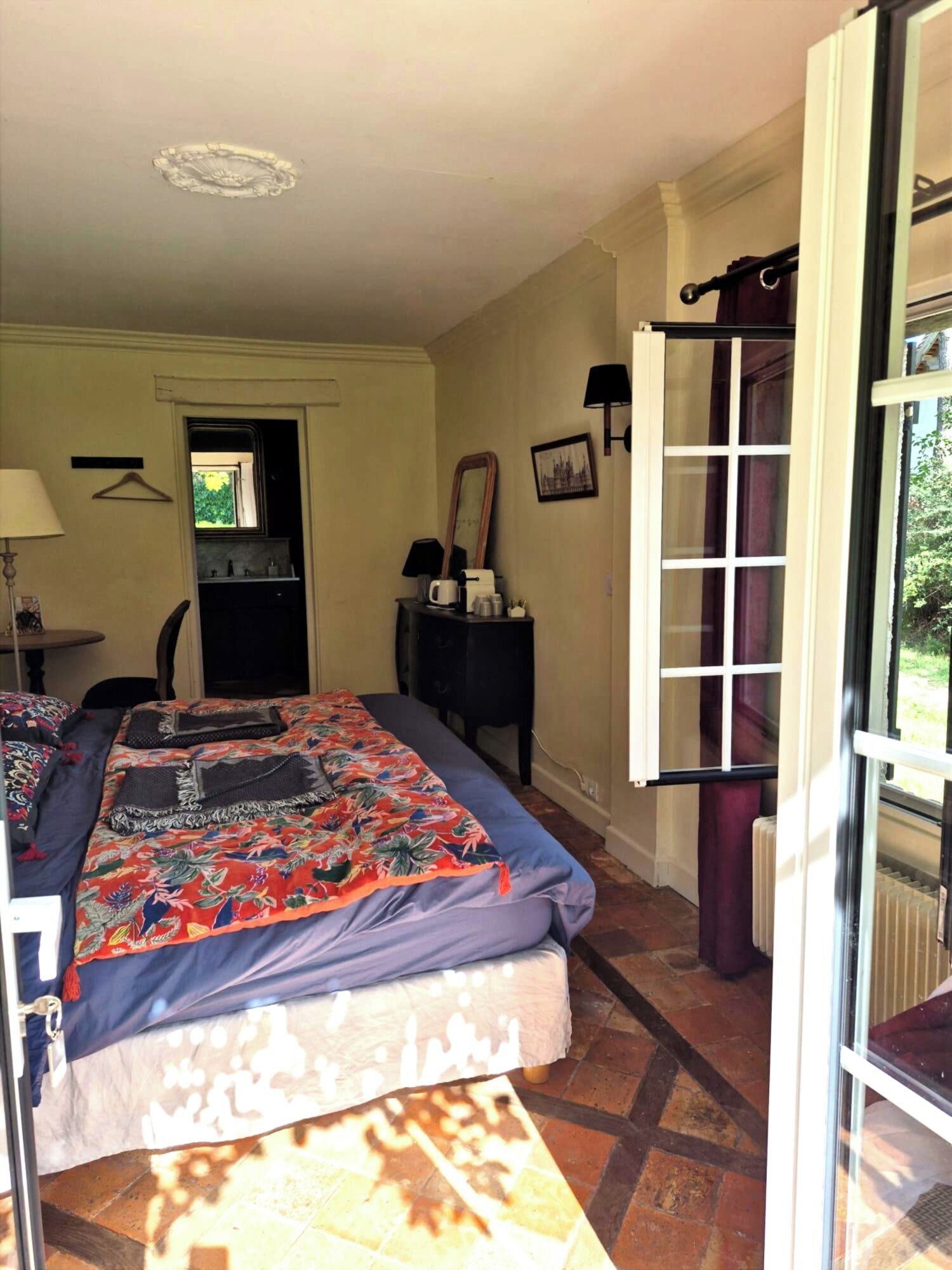 Quarto com cama, escrivaninha, cadeira, espelho e janela.