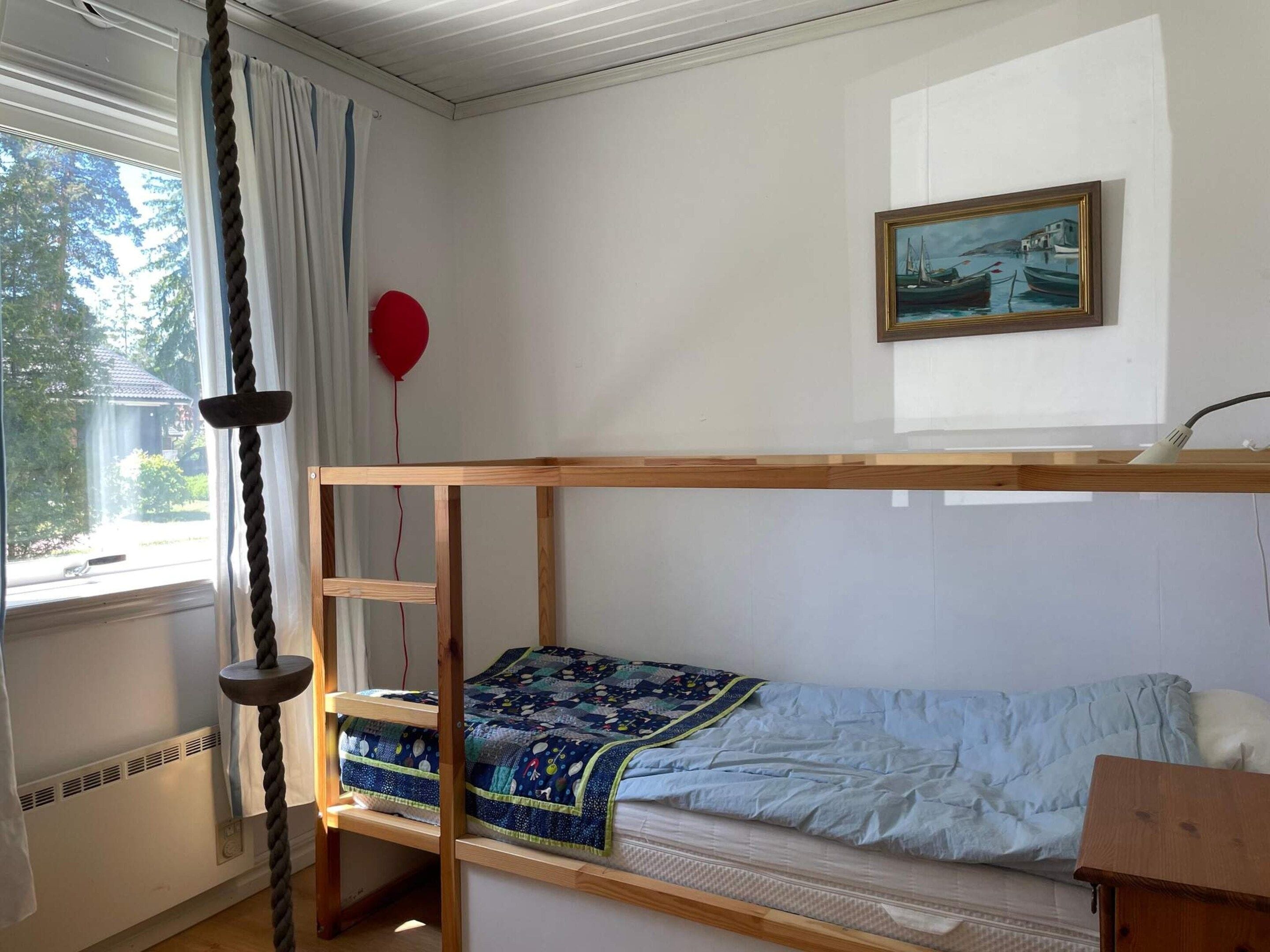 Quarto com beliche, janela, quadro na parede e um balão vermelho.