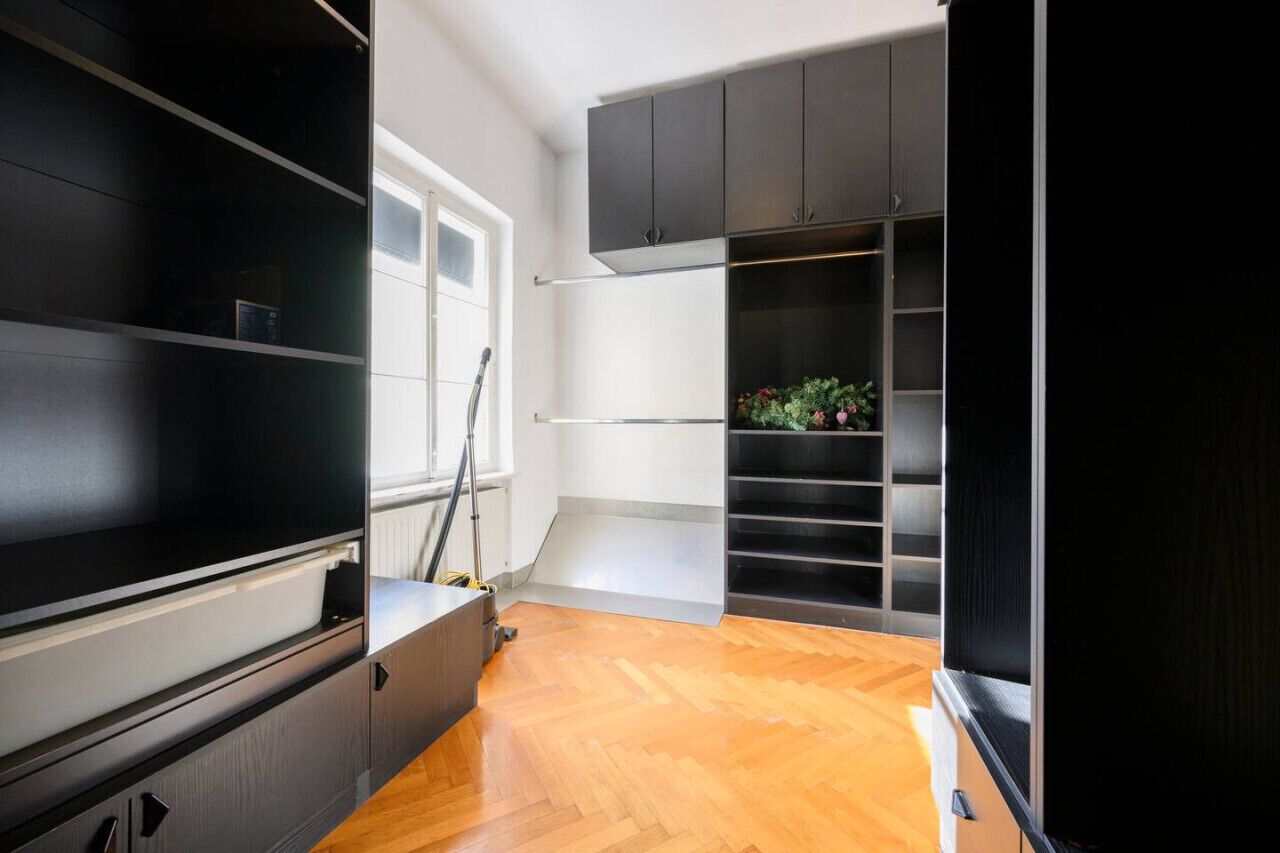 Cozinha moderna com armários pretos, piso de madeira e uma janela que oferece iluminação natural.