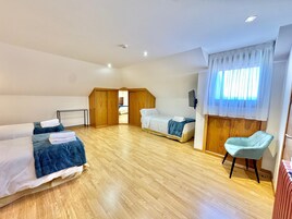Quarto de hotel com duas camas, um guarda-roupa de madeira, uma mesinha e uma cadeira.