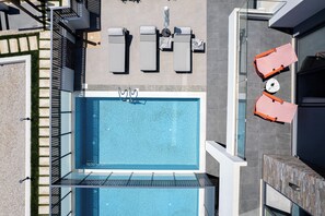 Uma área de piscina no terraço, com trampolim, espreguiçadeiras e uma fonte.