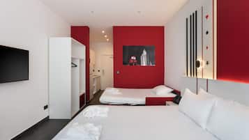 Quarto de hotel moderno com cama, televisão, parede de destaque vermelha e uma pintura.