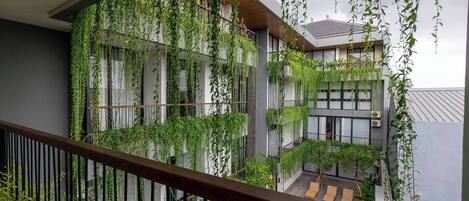 Um edifício com vários andares, jardins verticais e guarda-corpo de madeira na varanda.