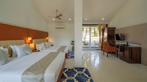 Quarto de hotel com duas camas, uma secretária com televisão e varanda com área de estar ao ar livre.