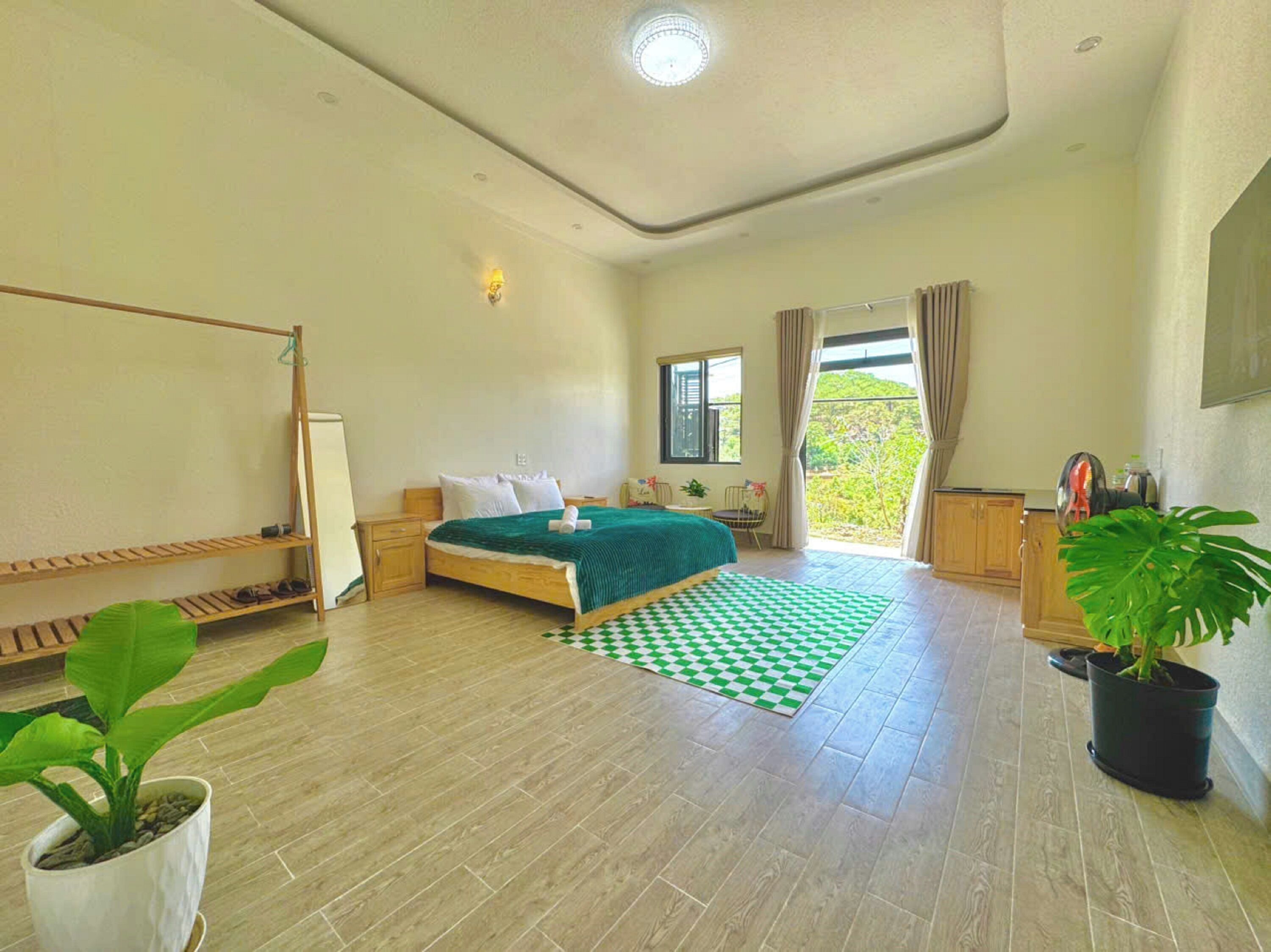 Quarto com cama, janela, planta e prateleira de madeira.