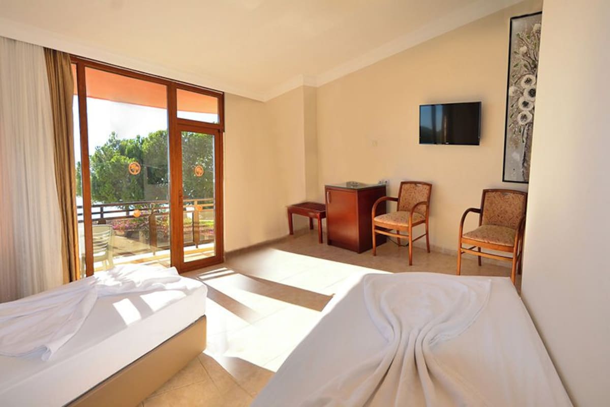 Quarto de hotel com duas camas, televisão, escrivaninha e uma cadeira.