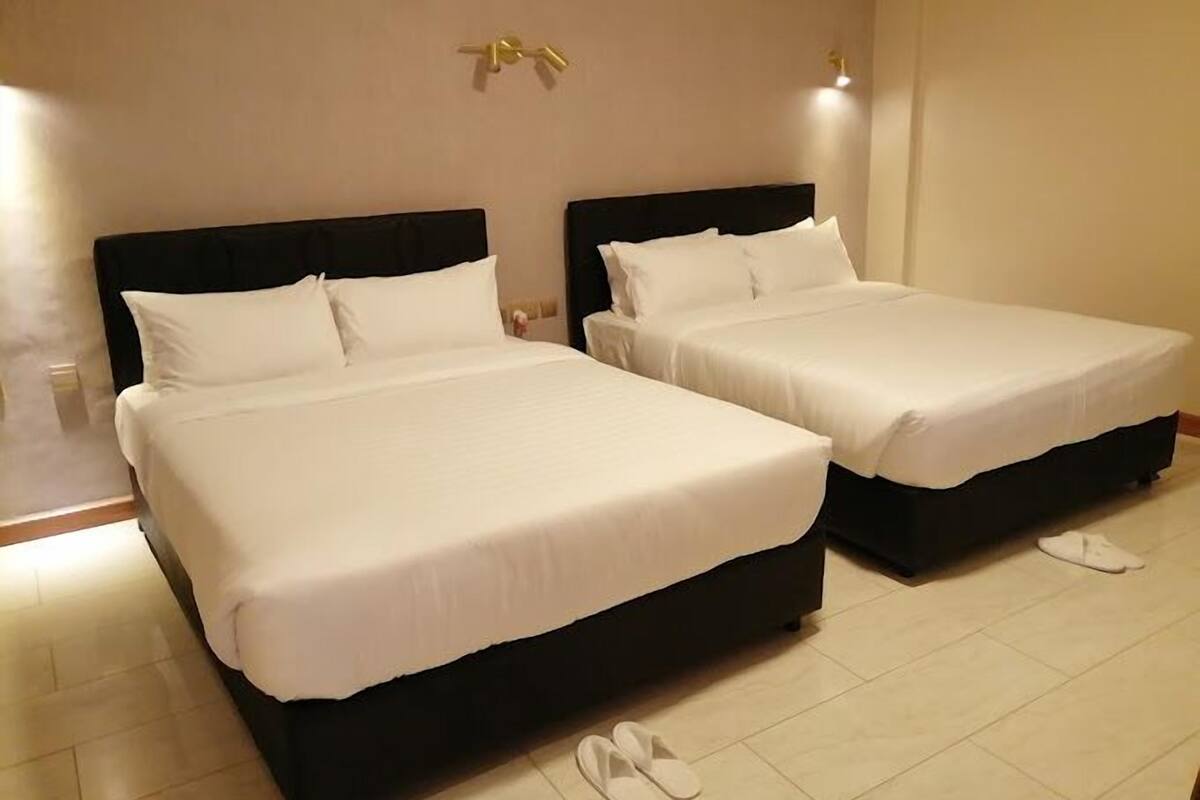 Duas camas de solteiro com cabeceiras pretas em um quarto de hotel.