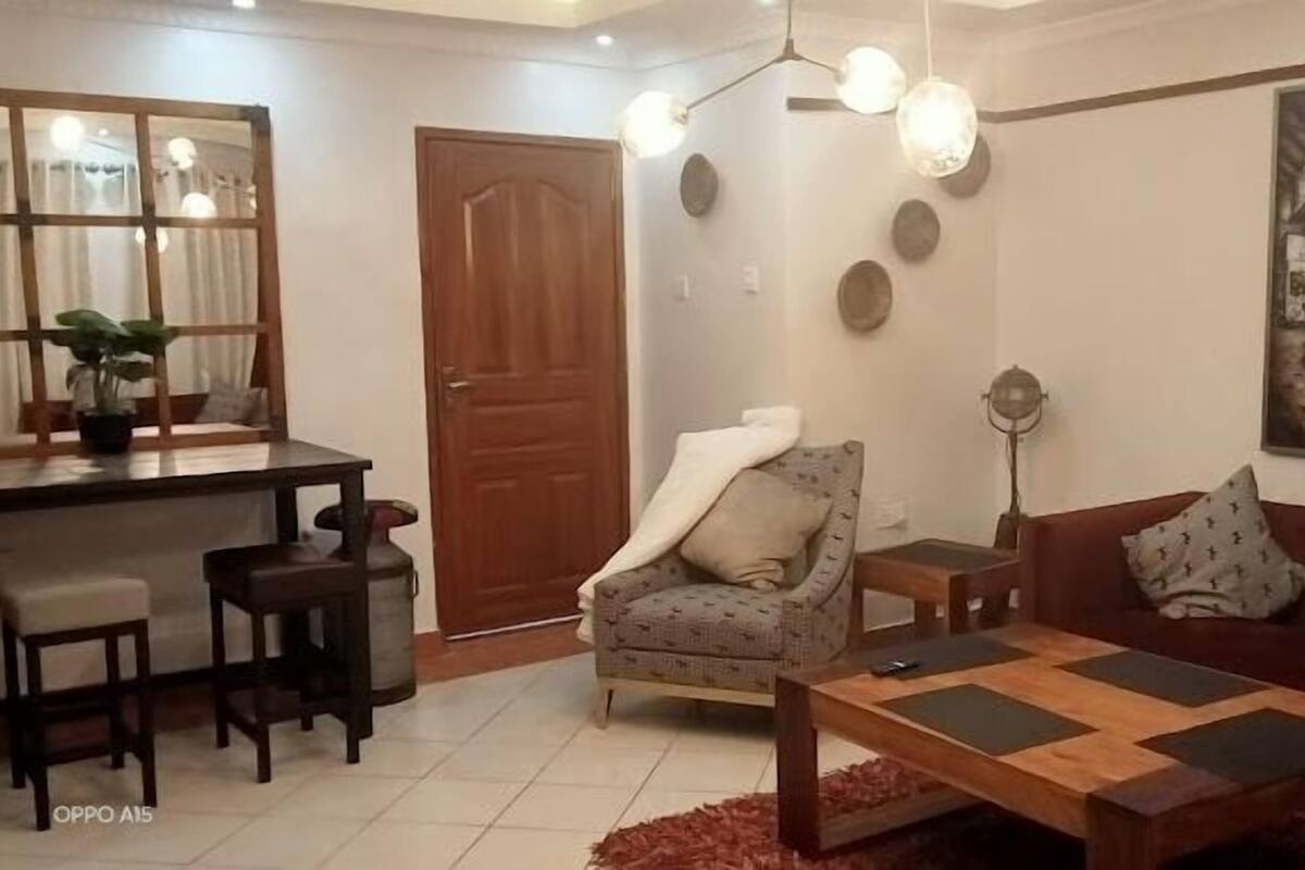 Uma sala de estar com uma mesa de centro de madeira, um sofá, uma poltrona, uma mesa de jantar e um quadro na parede.