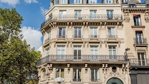Um edifício de vários andares com detalhes arquitetônicos elaborados, incluindo varandas com grades de ferro forjado e molduras decorativas.