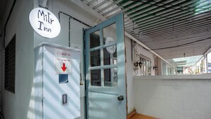 Entrada de hotel com uma placa indicando "Mitr Inn", teclado para acesso aos quartos e uma porta azul.