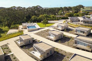 Um resort moderno com várias cabanas de madeira, piscina e um jardim bem cuidado.