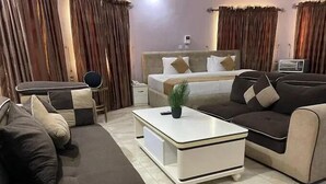 Uma sala de estar moderna com sofá, mesa de centro, televisão e cortinas.