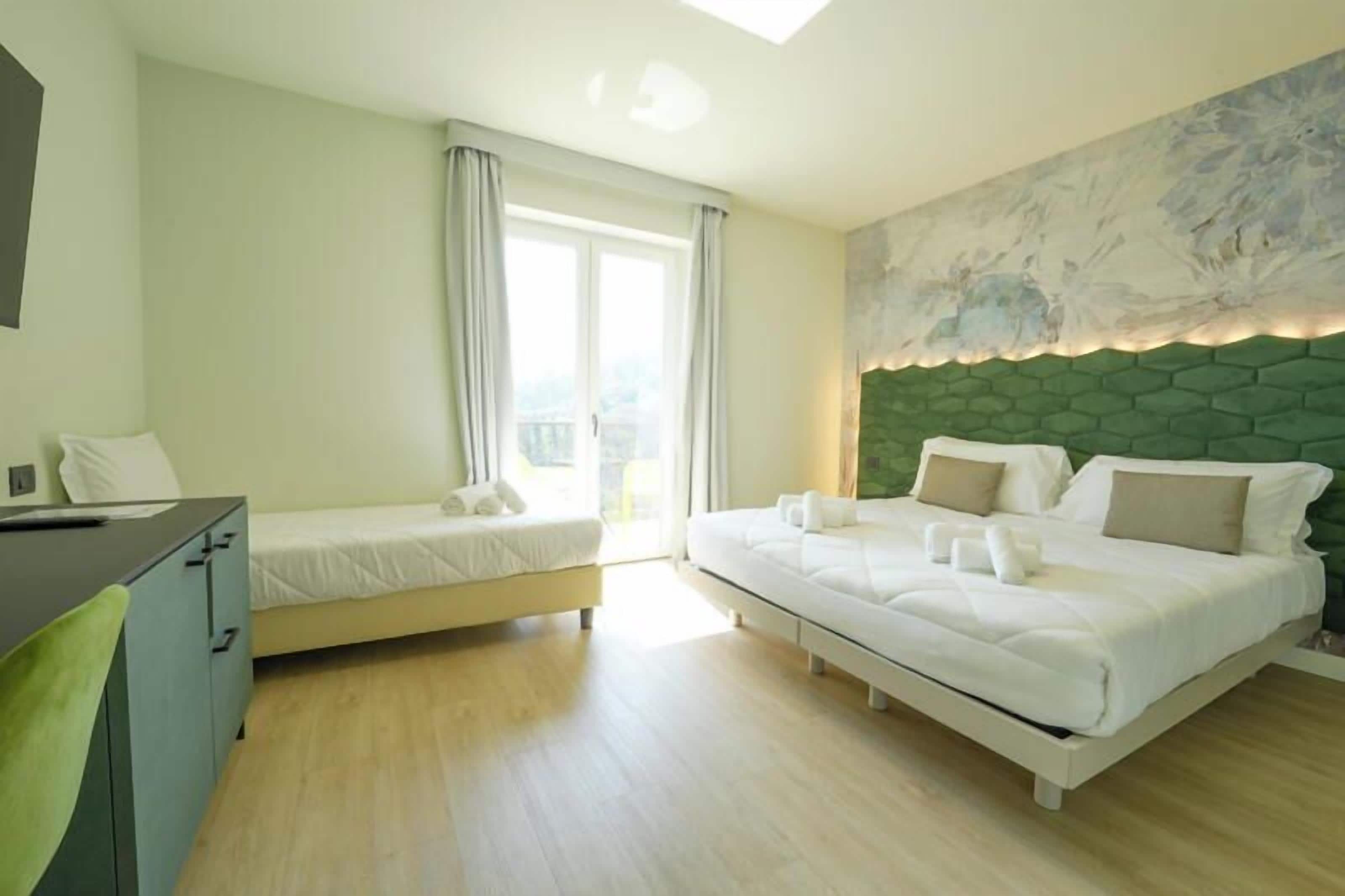 Quarto de hotel com cama, escrivaninha e janela.