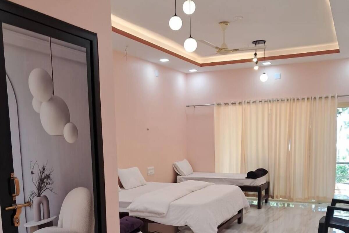 Quarto de hotel moderno com uma cama grande, uma cama menor, área de estar e banheiro.