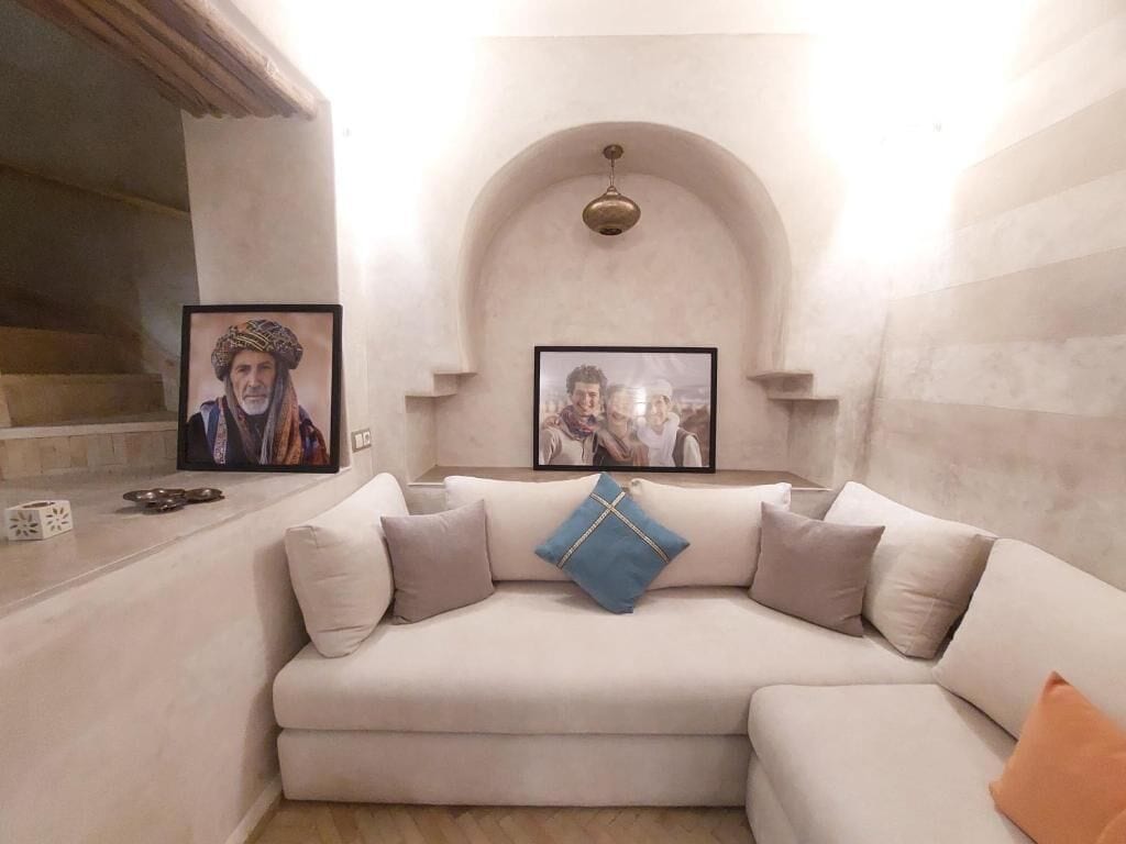Uma sala de estar com sofá, quadros nas paredes e uma escada.