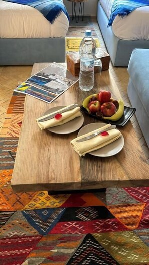 Uma mesa de centro de madeira com pratos, guardanapos, uma garrafa de água e uma tigela de frutas.