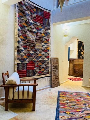 Um quarto com parede estampada, uma cadeira de madeira, um tapete estampado e um objeto decorativo na parede.