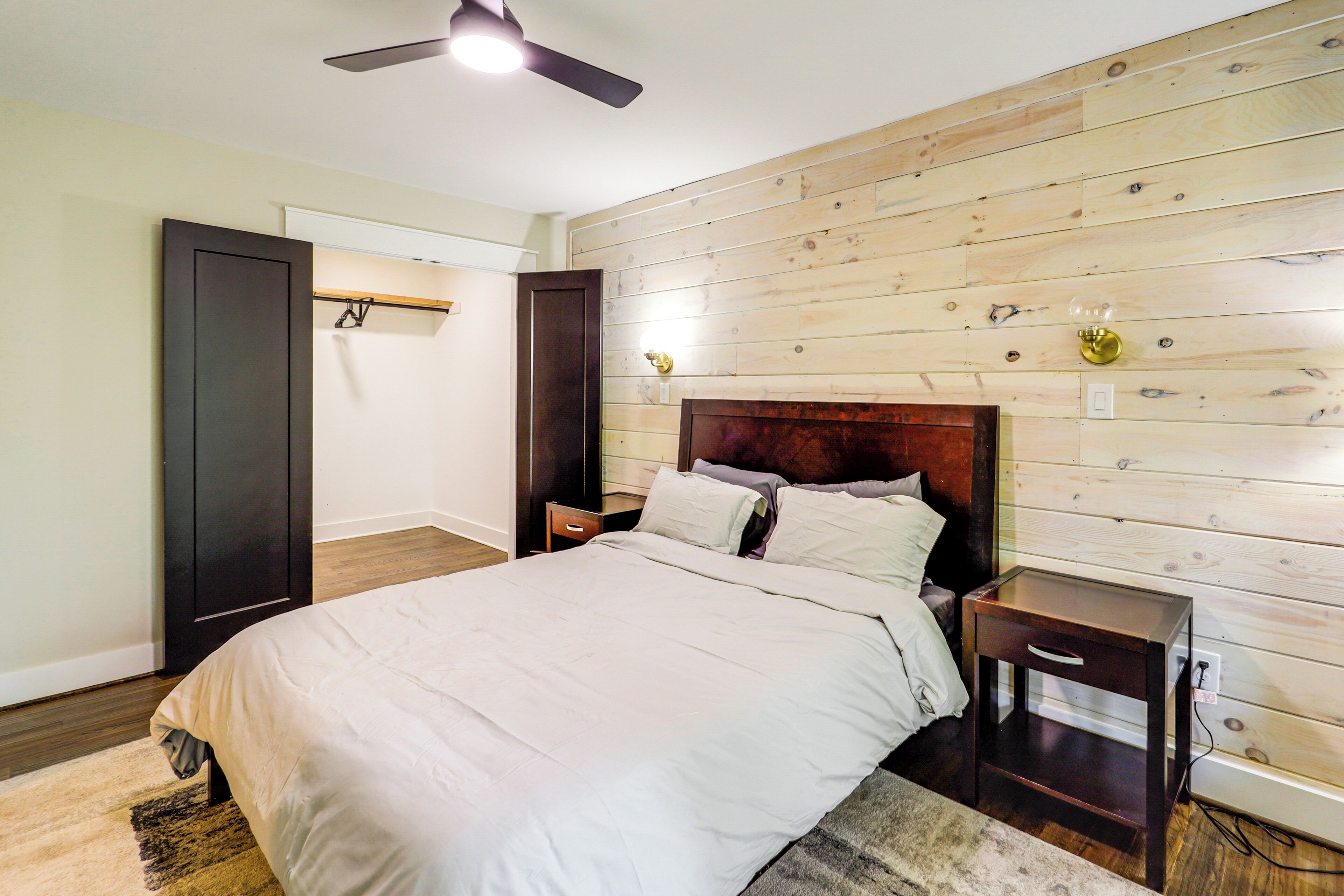Quarto com uma cama grande, paredes de painel de madeira, ventoinha de teto e mesa de cabeceira.