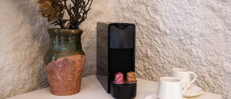 Uma mesa com um vaso, uma revista, um alto-falante preto e duas xícaras brancas.