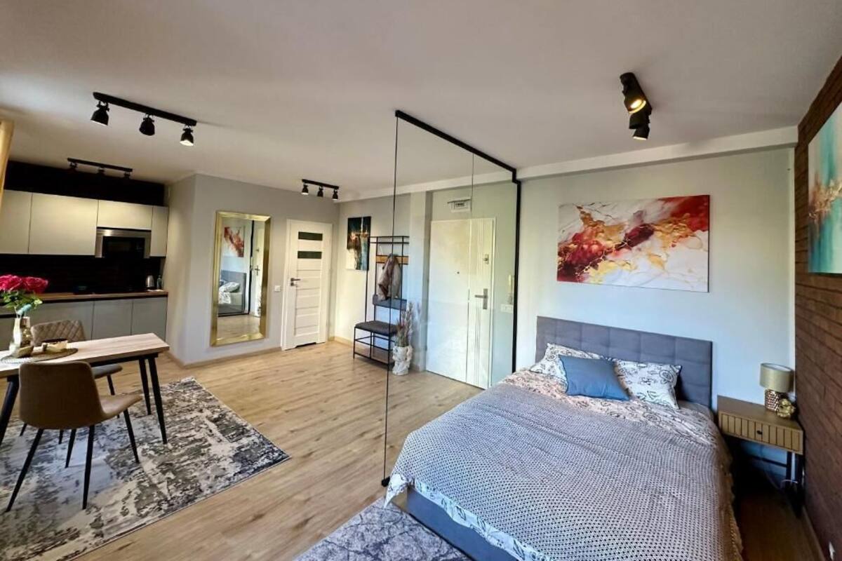 Quarto moderno com cama grande, escrivaninha e área de refeições.