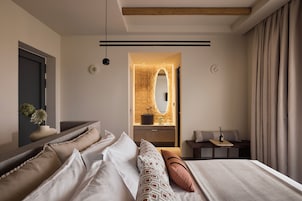 Quarto moderno com uma cama grande, uma toucador com espelho e uma pequena mesa com abajur.