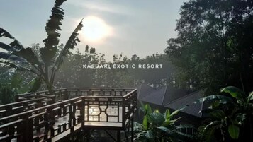 Um deck de madeira no Kasuari Exotic Resort, com vista para o verdejante entorno e um céu claro.