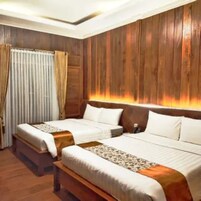 Quarto de hotel com duas camas, painéis de madeira nas paredes e uma janela com cortinas.