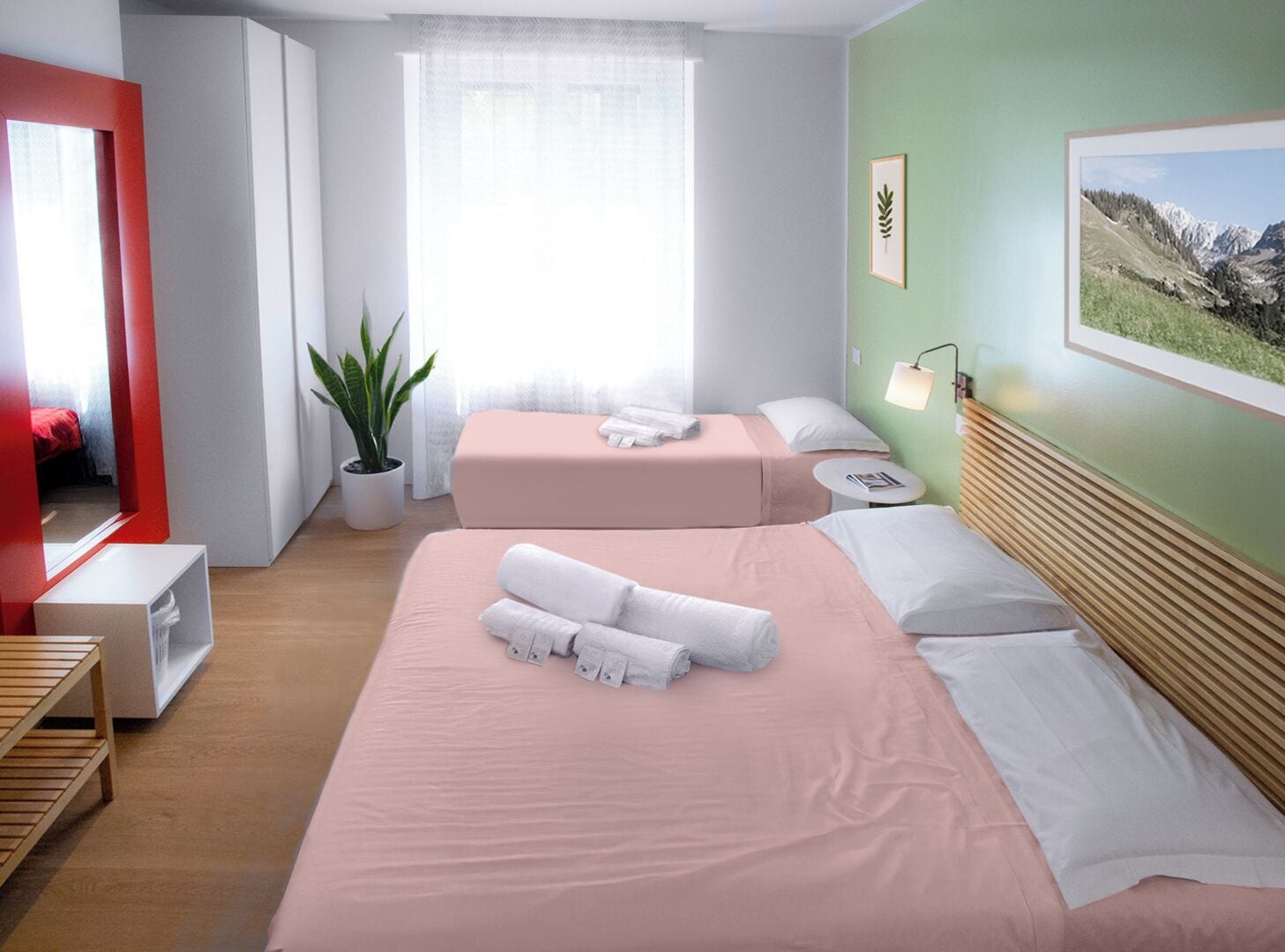 Quarto de hotel com uma cama grande, um sofá pequeno, uma planta em vaso, uma janela com cortinas leves e um quadro na parede.